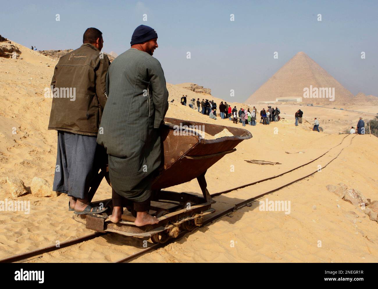 Egyptian archaeology workers ferrying sand in trolleys on rail tracks ...