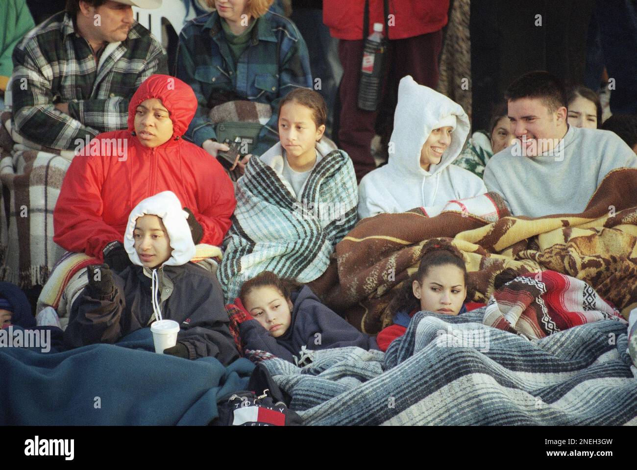 A crowd of people huddle under blankets to keep warm before the start ...