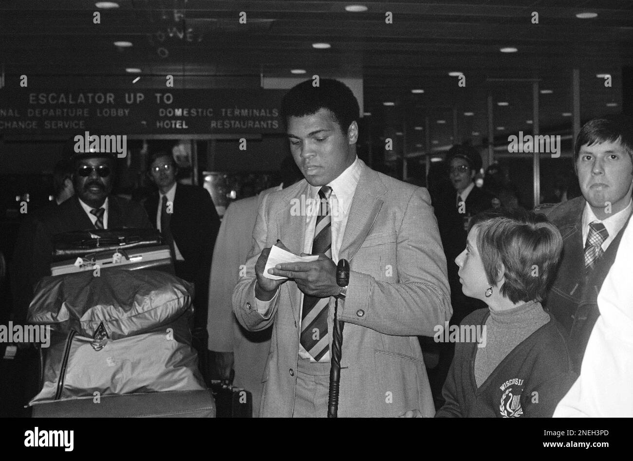 Heavyweight champion Muhammad Ali signs an autograph for a young fan ...