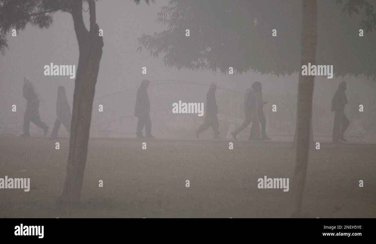 People walk as fog envelops Lahore, Pakistan on Friday Jan. 8, 2010 ...