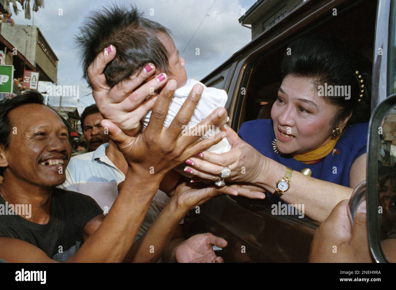 Former Philippines First Lady Imelda Marcos reaches out to hold a baby ...