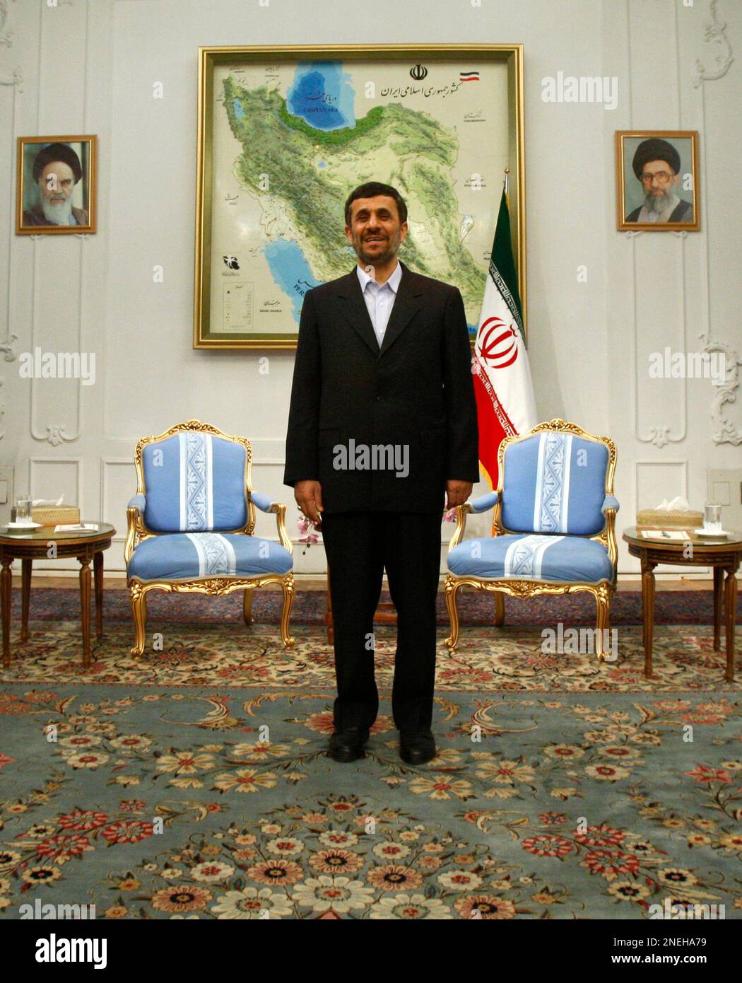 Iranian President Mahmoud Ahmadinejad stands in front of Iran's map ...