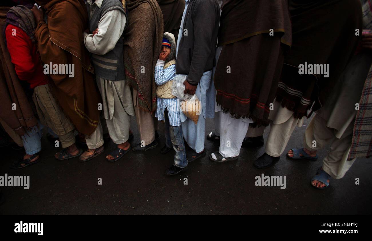A Pakistani boy lines up with other men to get rice ration during a ...