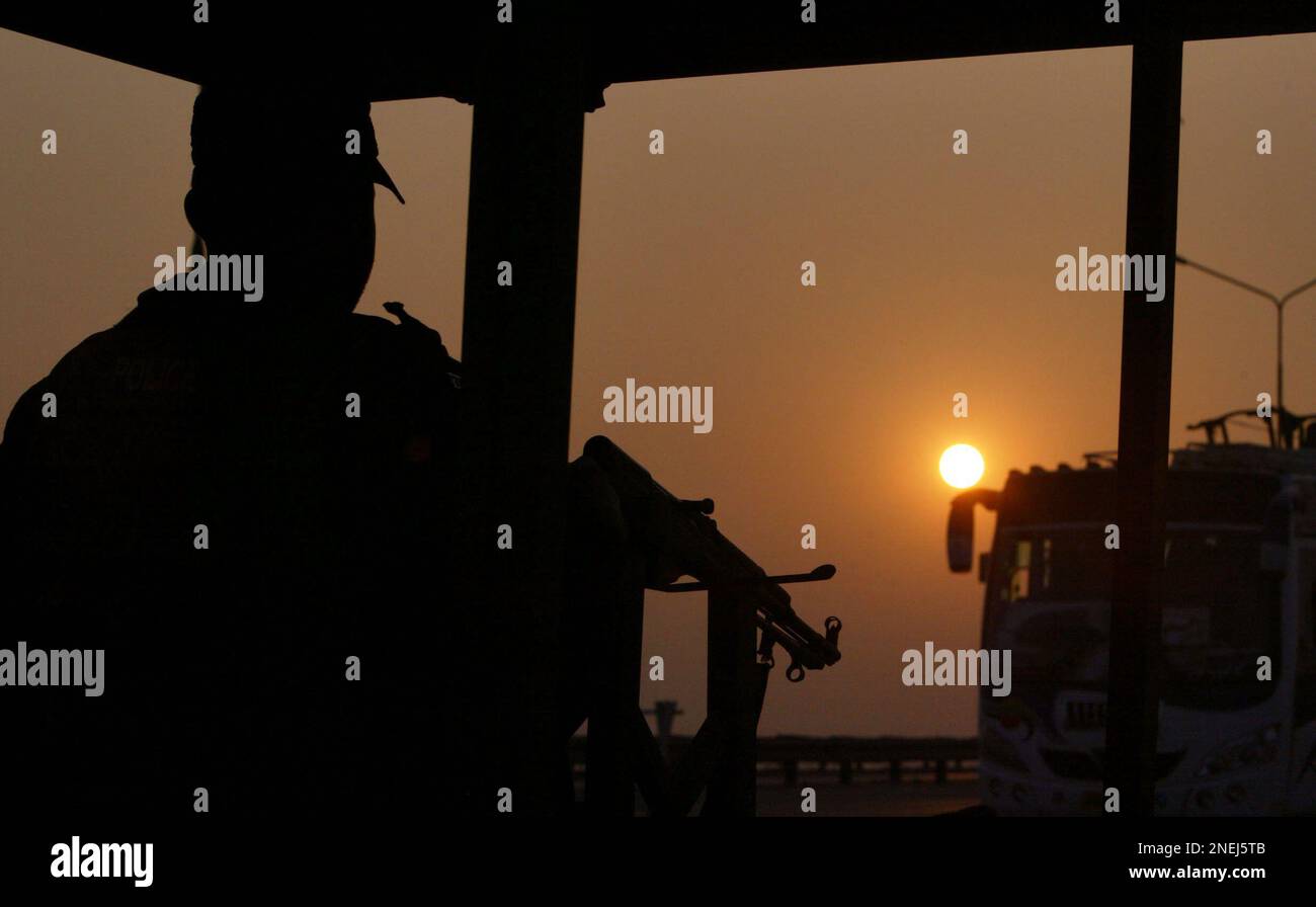 A Pakistani police officer mans a checkpoint as the sun sets marking ...