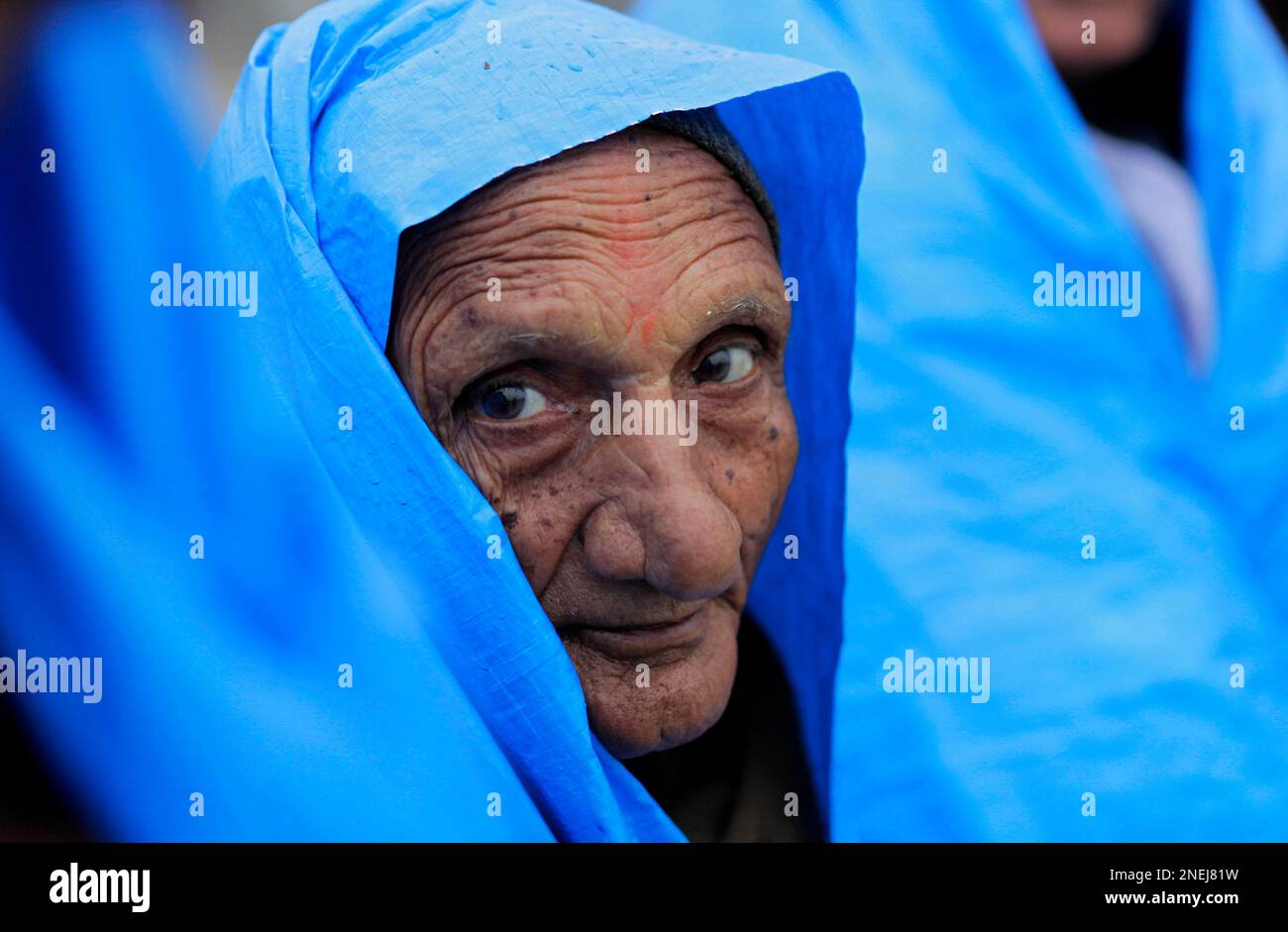A Indian Hindu devotee take cover under sheets of plastic to protect ...