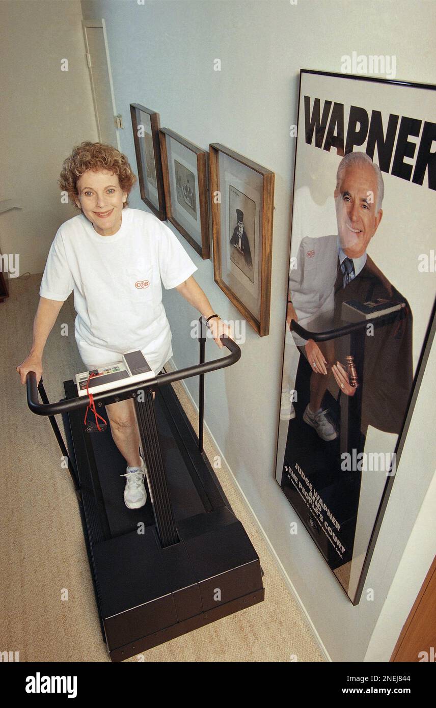 Mickey Wapner poses on her tredmill near a photograph of her husband at ...