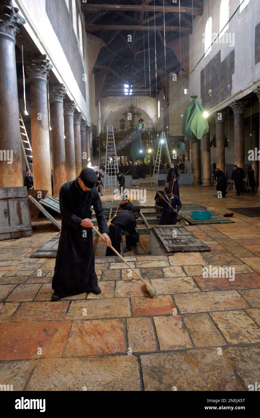 Greek Orthodox clergymen use brooms to clean the church floor during ...