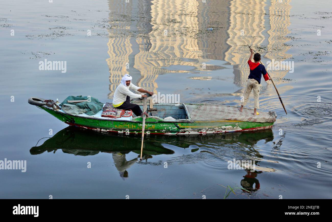 An Egyptian fisherman rows his boat past the Nile City Towers building ...