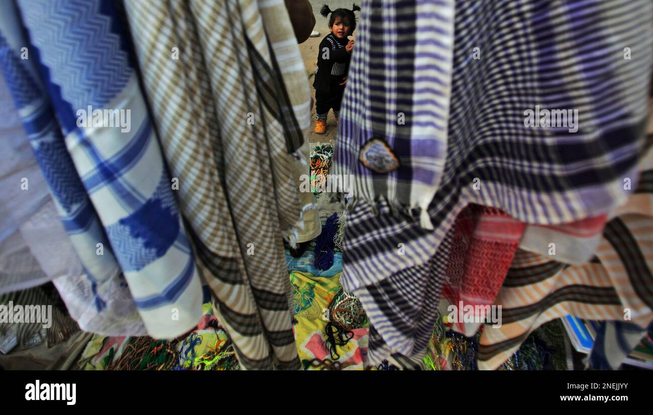A Pakistani girl, standing with her mother, not seen, look at scarves ...