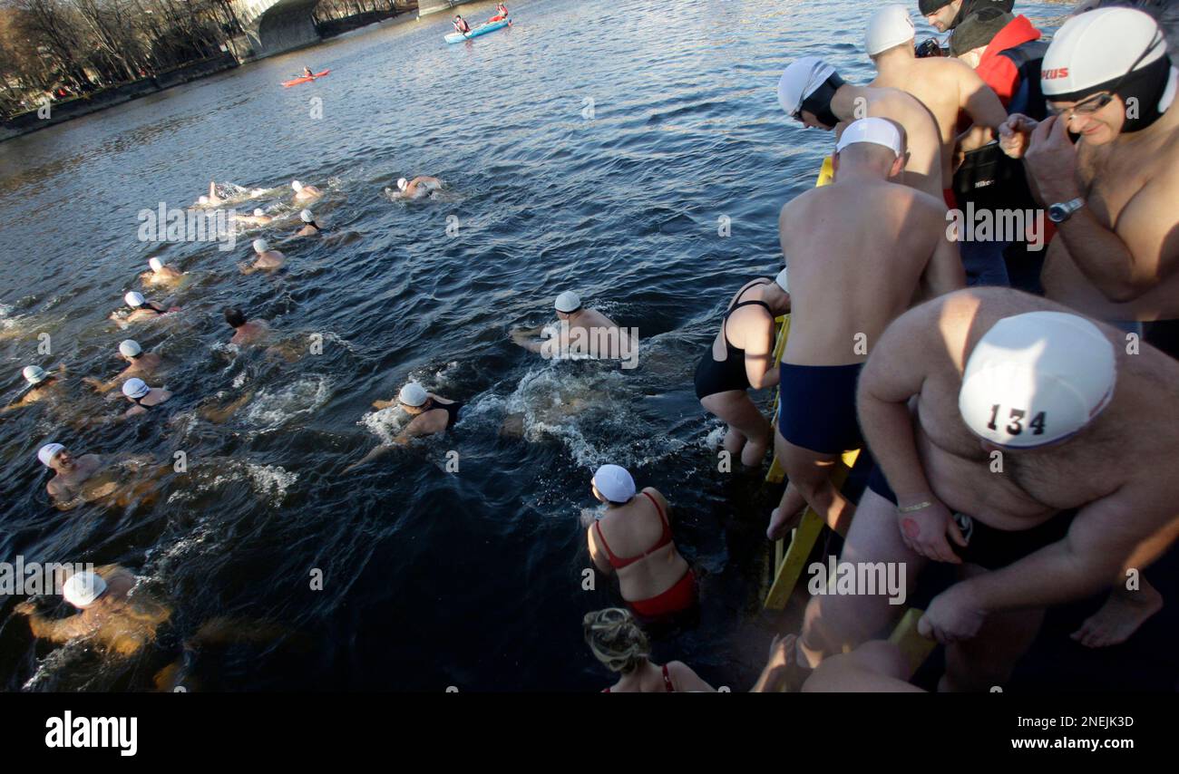 Polar swimmers climb down ladders into the Vltava River for their ...