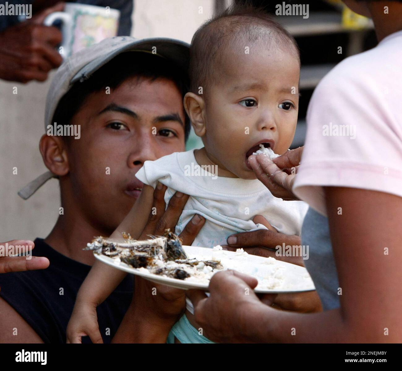 A Mayon volcano child evacuee is fed by her mother as they wait for the ...