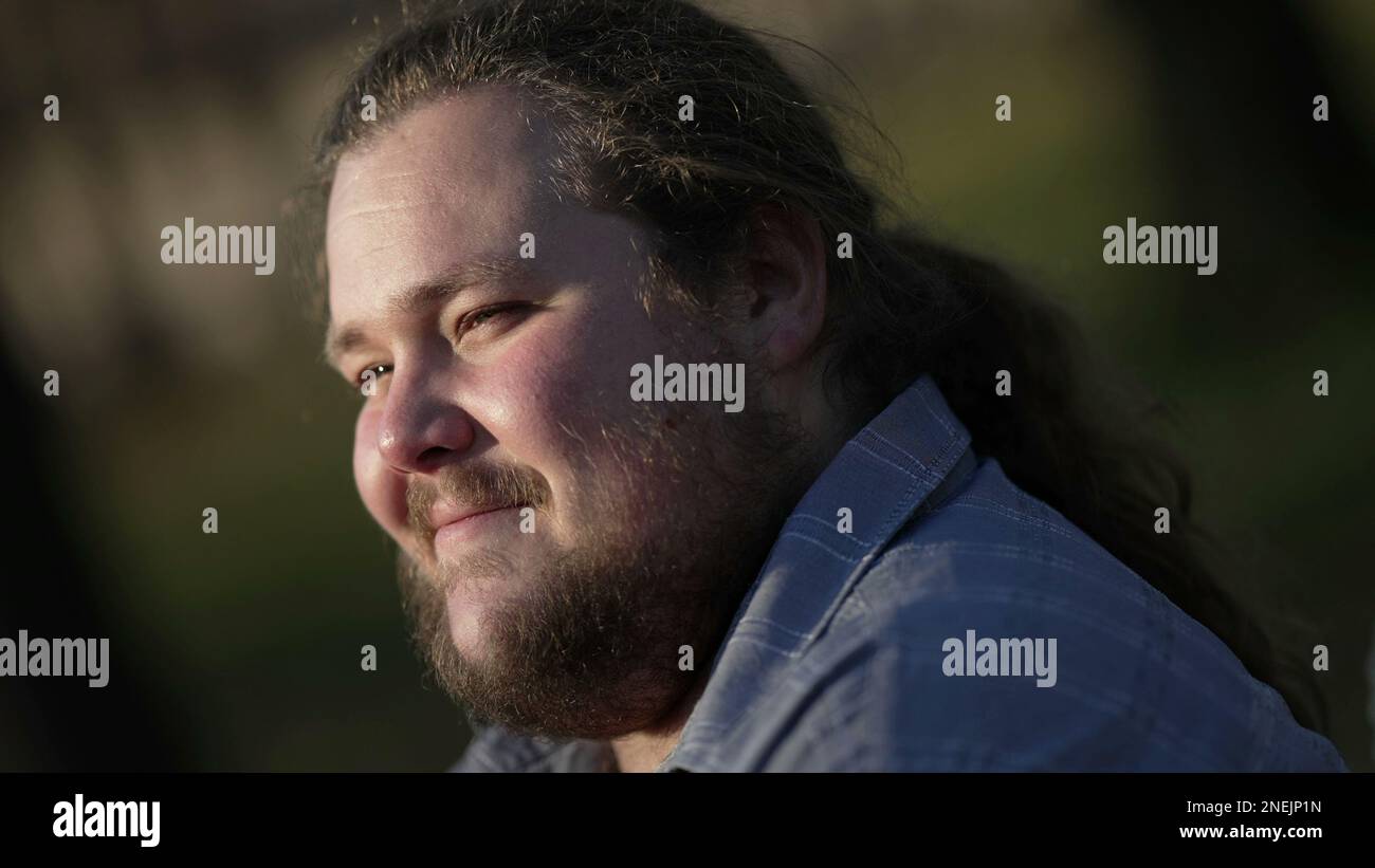 Relaxed young man sitting at park in nature feeling happy ...