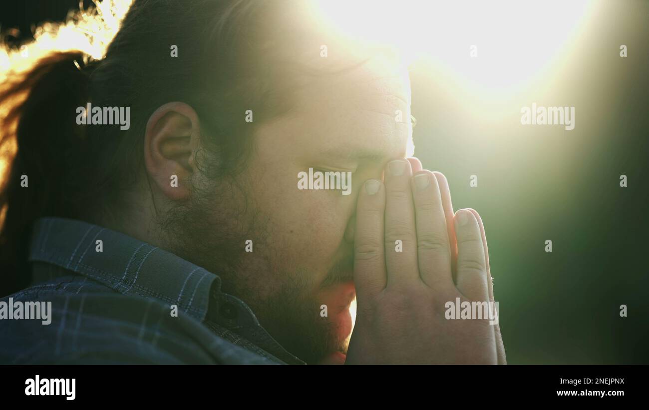 Spiritual young man praying to GOD outdoors in nature. Profile face ...