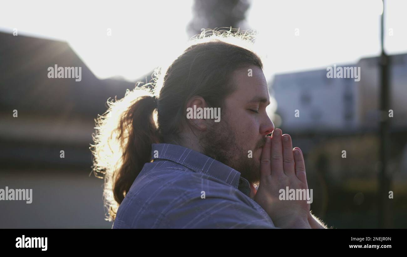 Spiritual young man praying to GOD outdoors in sunlight. A male ...