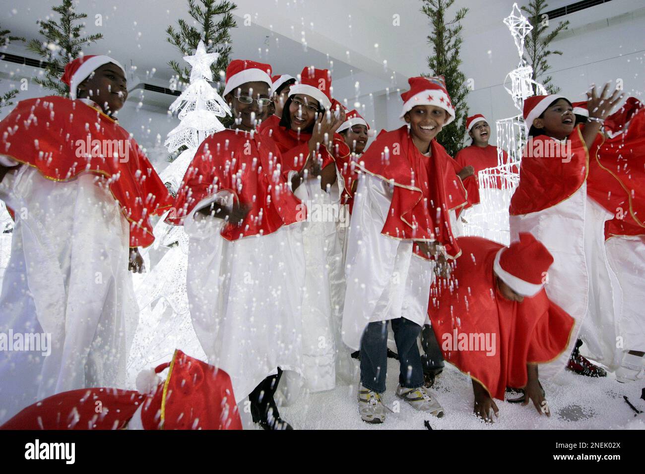 Malaysian children wear Santa Claus outfits as they play with fake snow ...