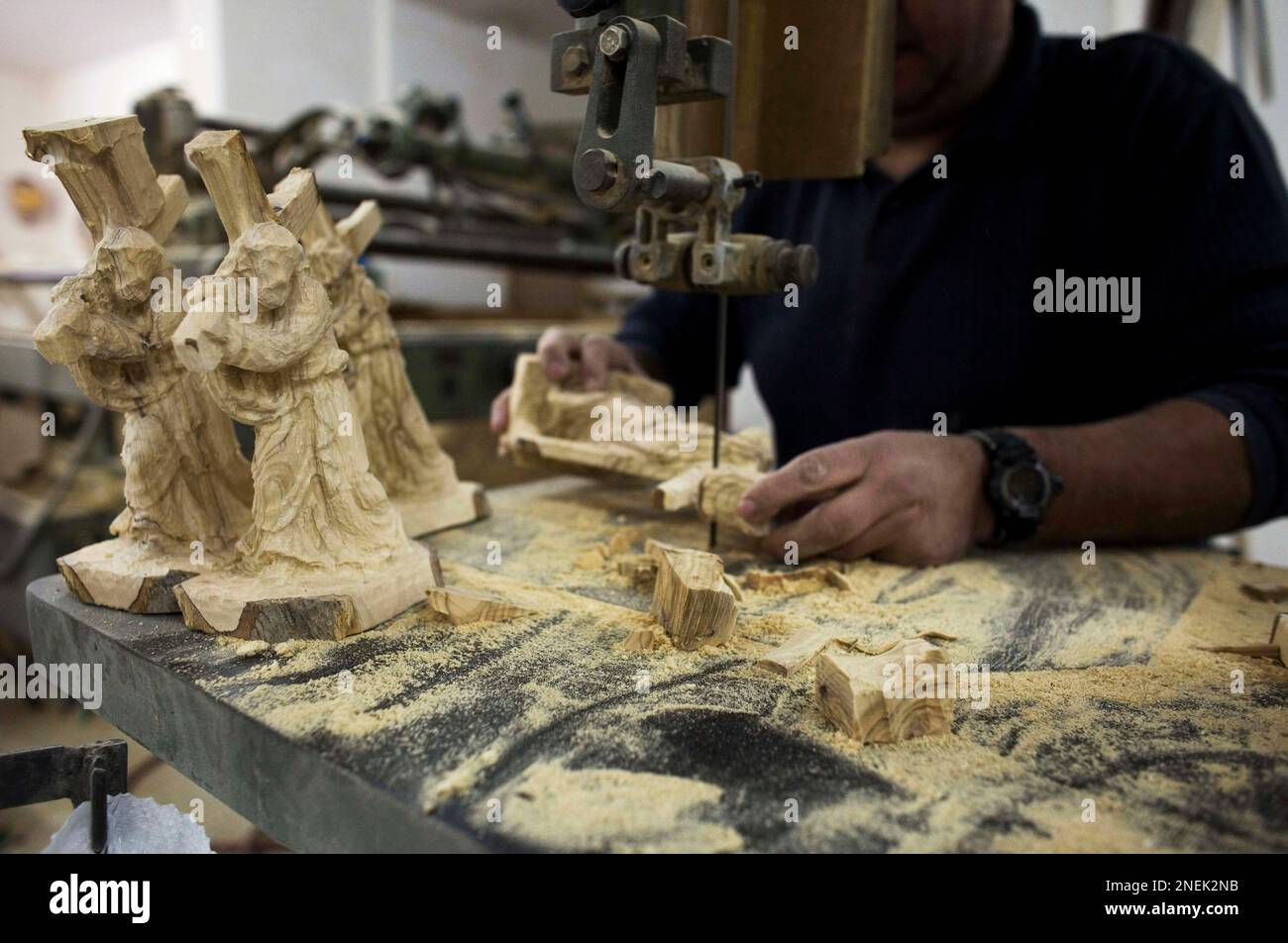 A Palestinian craftsman works on olive wood figurines at a factory in ...