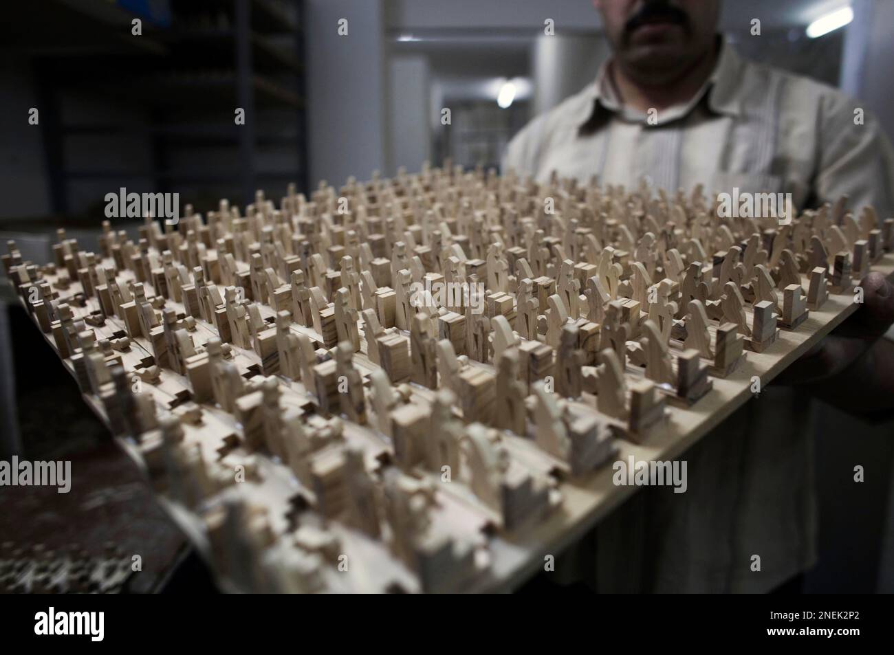 A Palestinian craftsman holds a tray with olive wood nativity scenes at ...