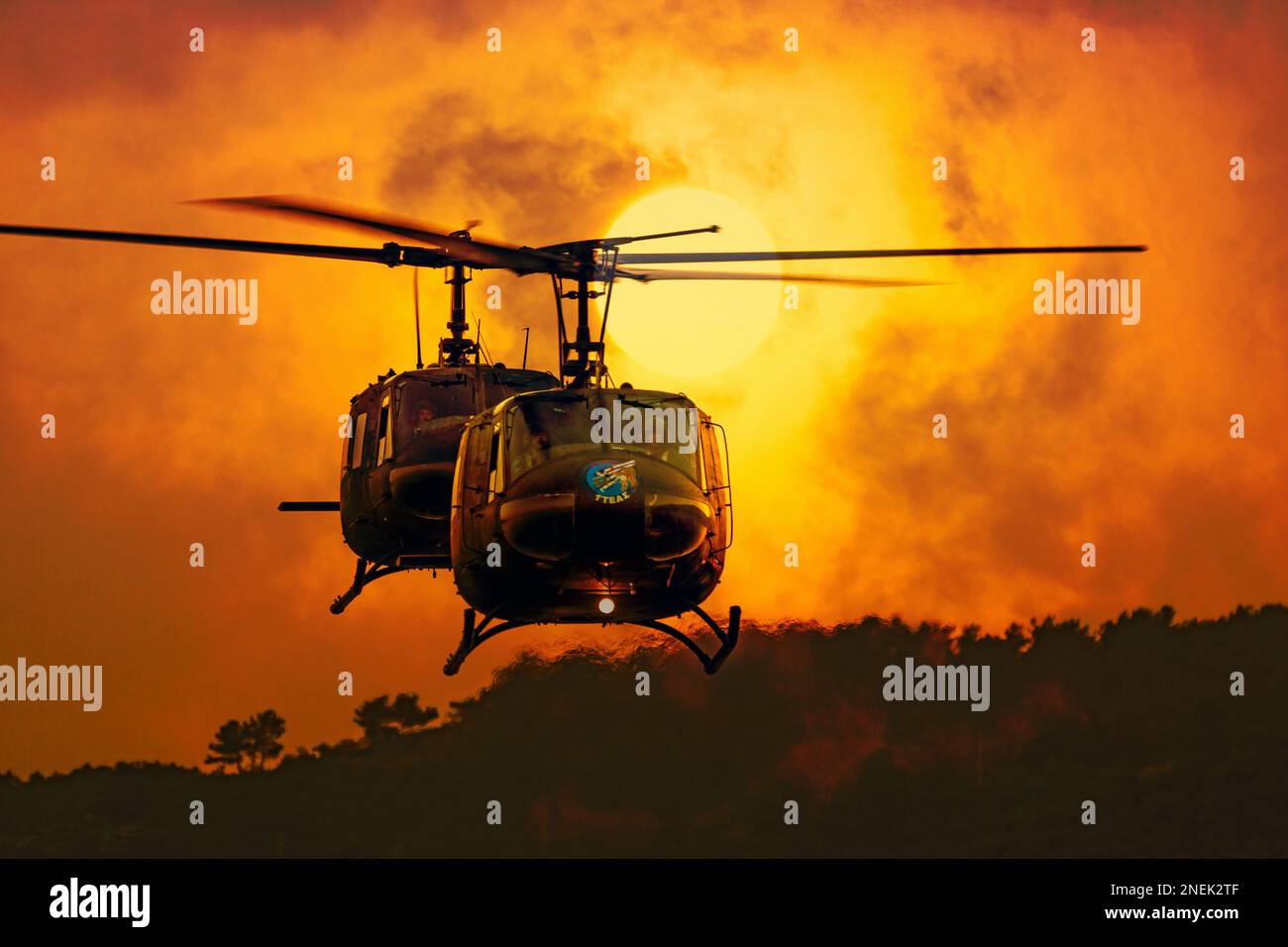 A utility military helicopter flying above the forest at sunset time ...