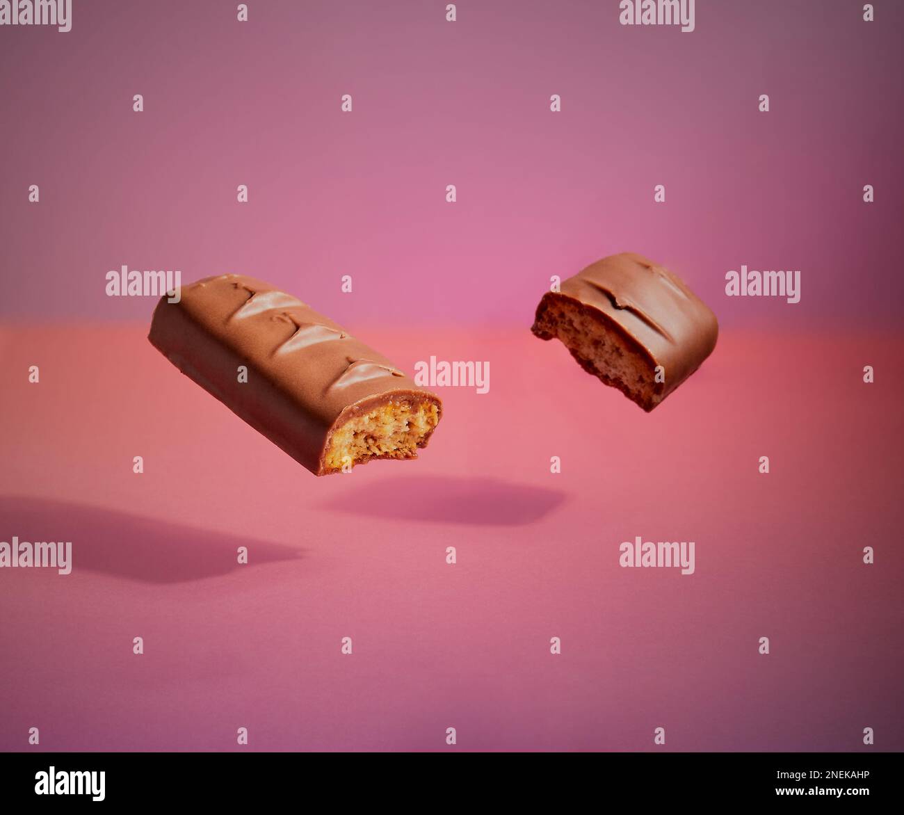 Floating chocolate bar snapped in two on a cool pink gradient ...