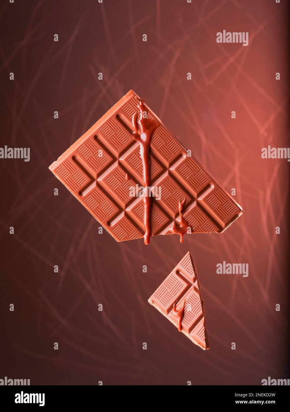 Flying chocolate bar with chocolate running down it isolated on a brown ...