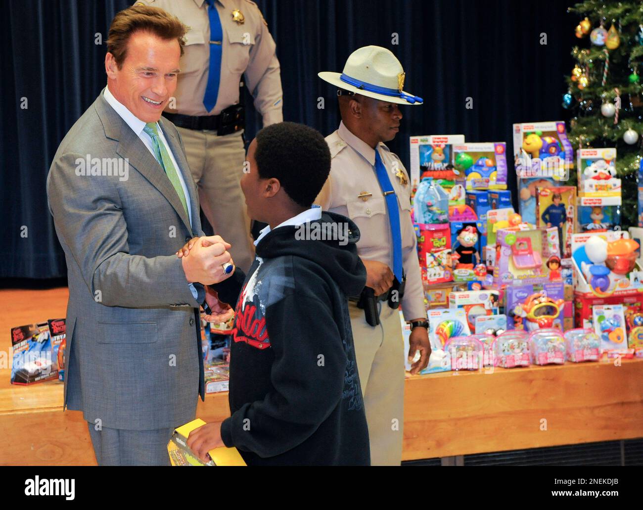 Calif. Gov. Arnold Schwarzenegger hands a gift to Isaiah Cooper, 10, at ...