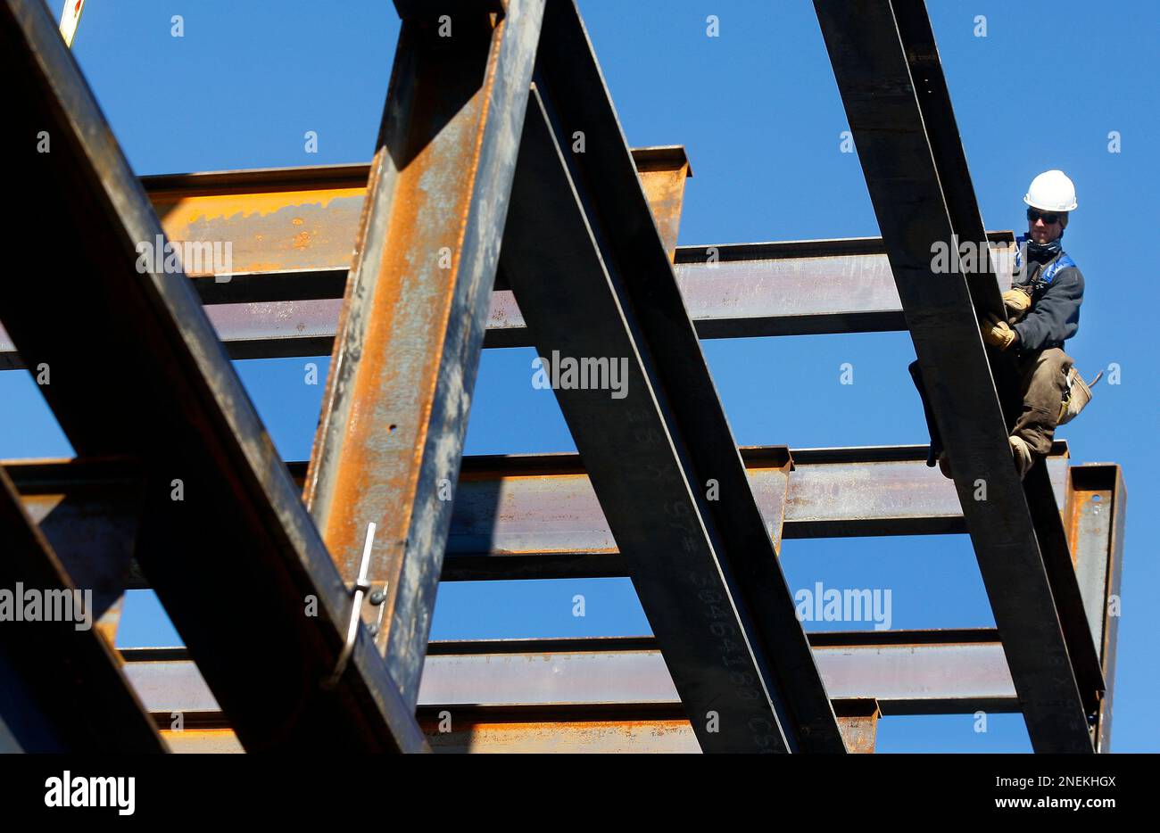 A worker guides a steel beam into place on a new building construction ...
