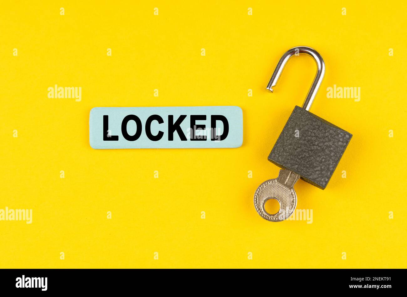 On the yellow surface lies an open lock with a key, next to it is a ...