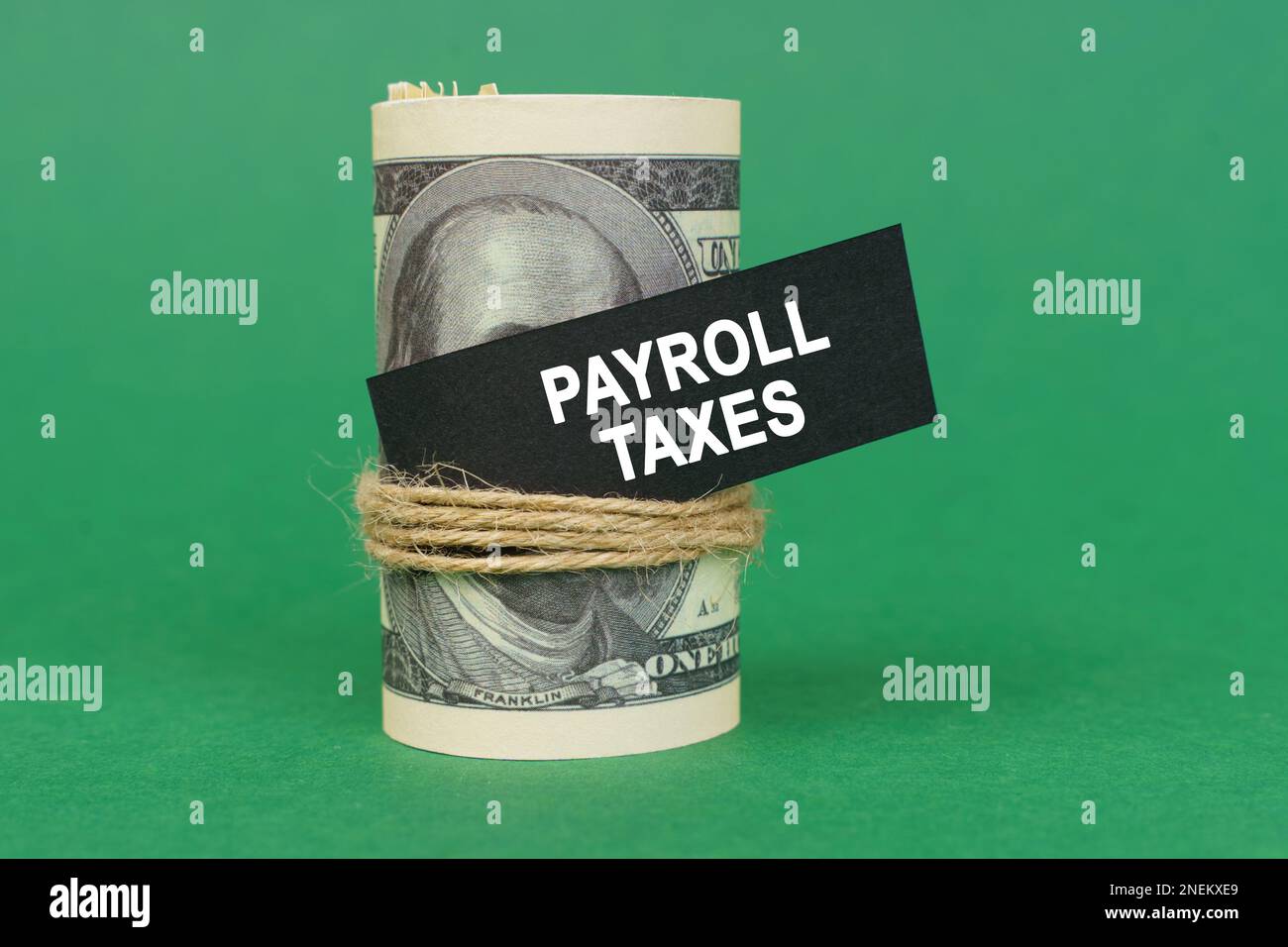 Business concept. On a green surface, rolled dollars with a black sign ...