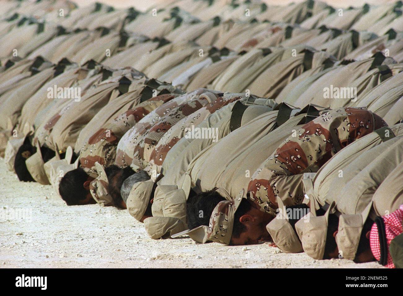 Some 600 Kuwaiti volunteers kneel in prayer after they graduated from a ...