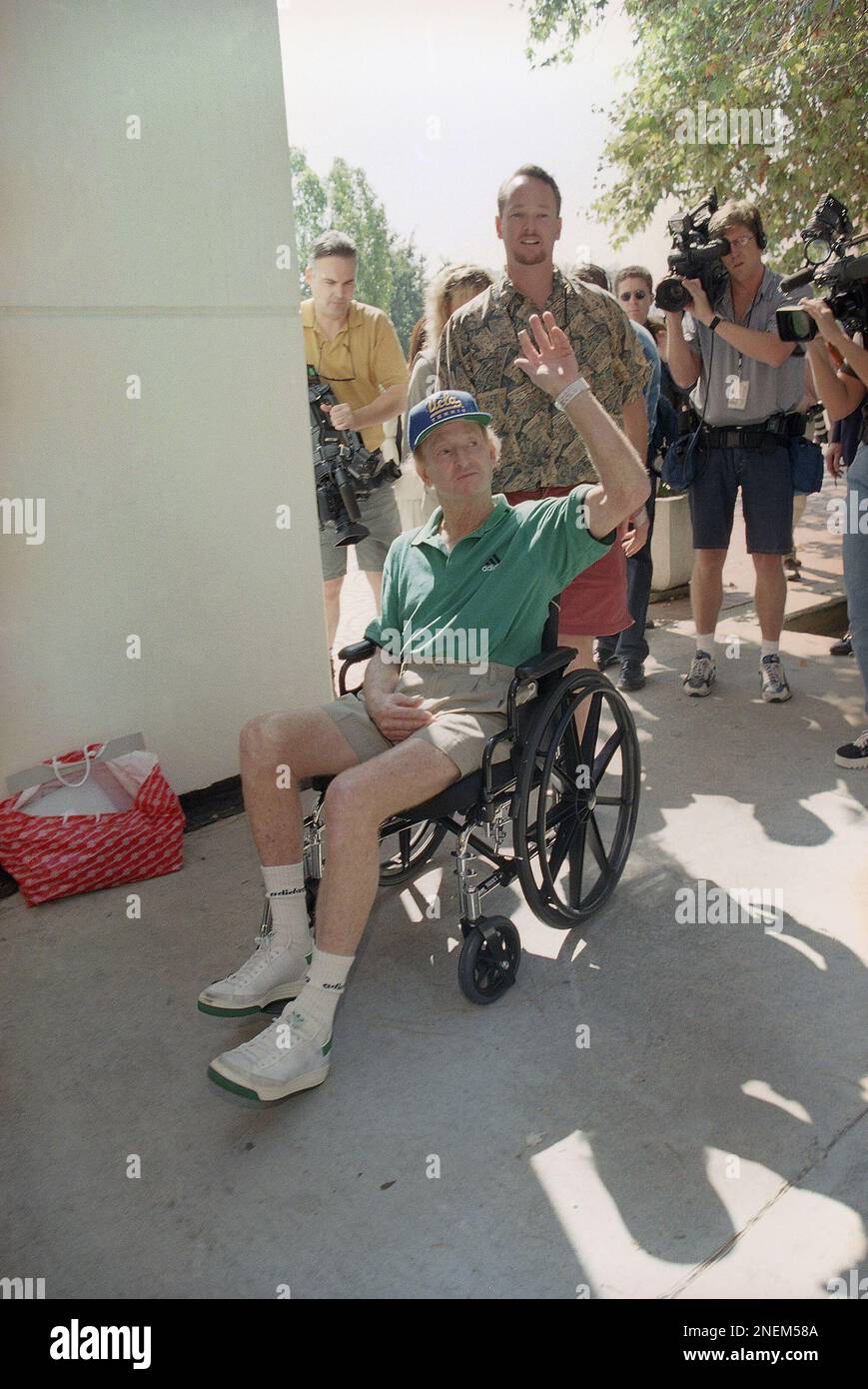 Rod Laver, 60, gives a wave as his son, Rick, pushes his wheelchair ...