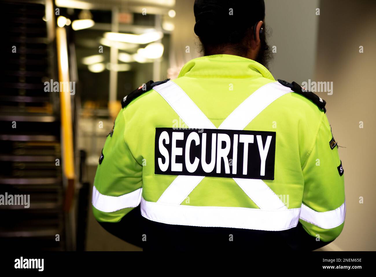 The rear view of a person in a neon green jacket with a security sign ...