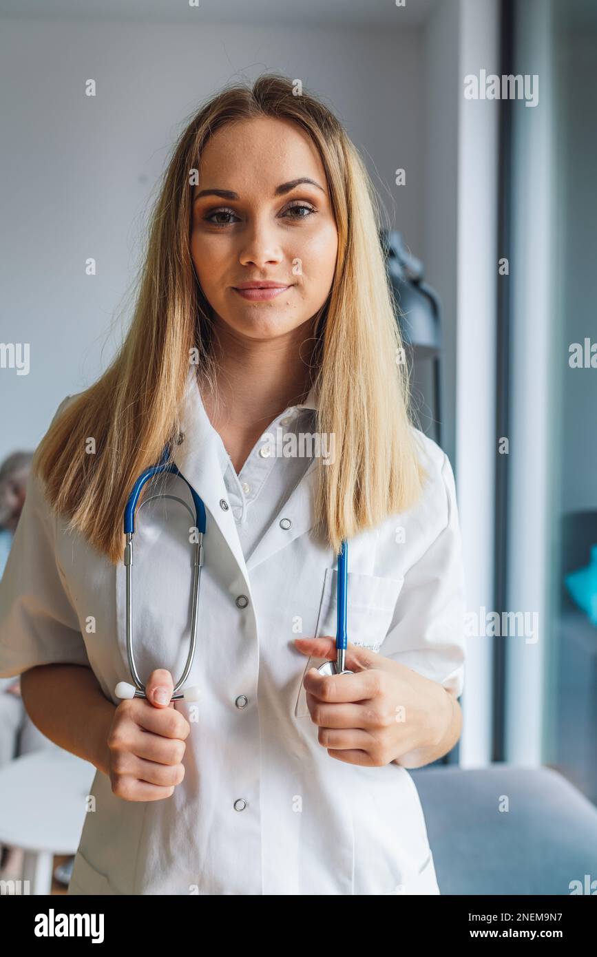 Vertical portrait of young blonde nurse with a stethoscope around her ...