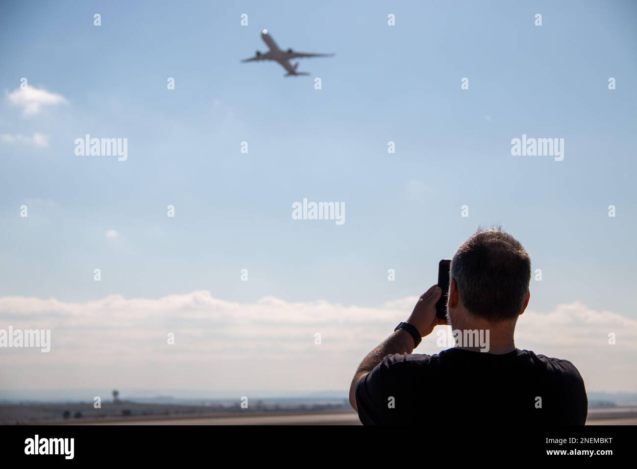 Slightly bald adult man dressed in black watching and pointing as ...