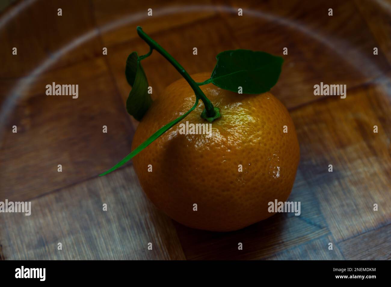 View of an organic mandarin with green leaf on a plate. Dark food Stock ...