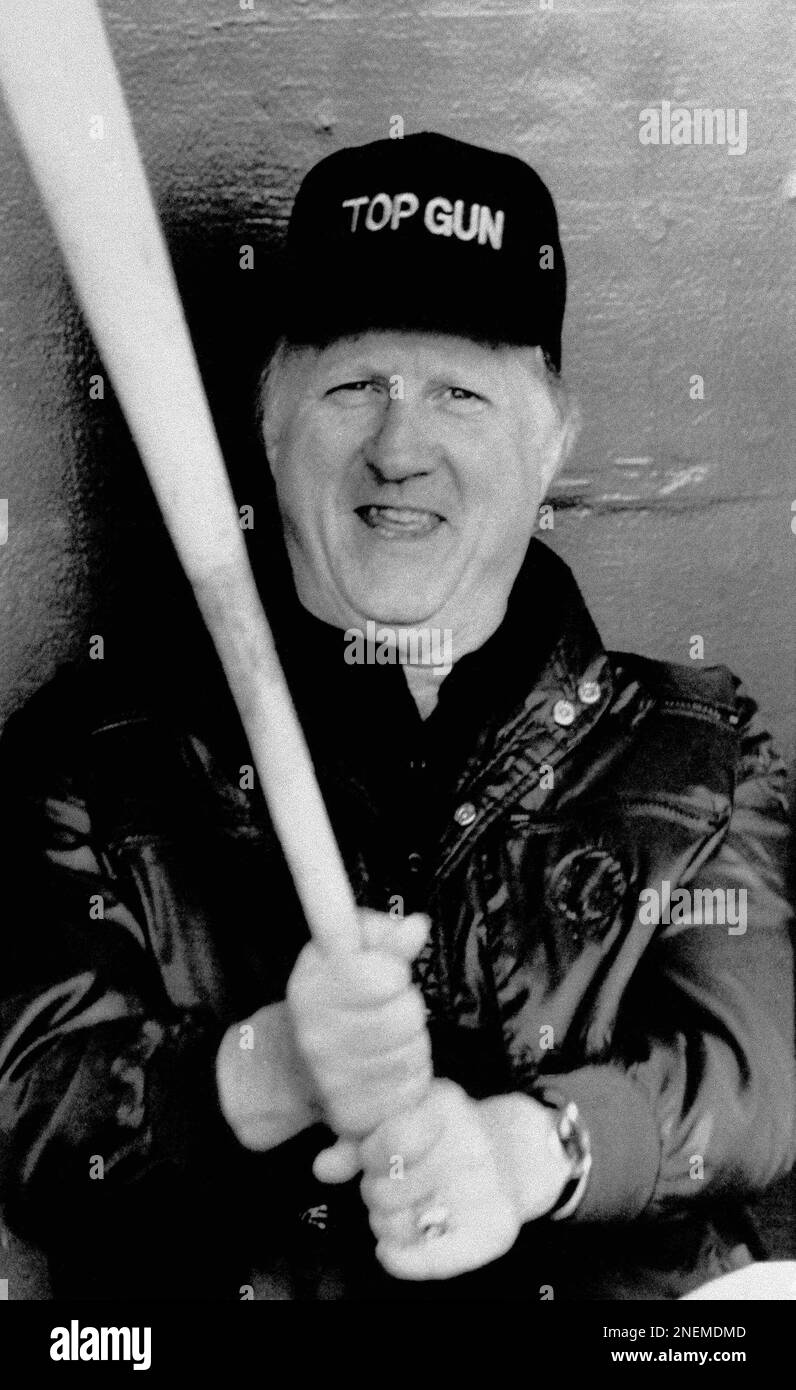 Yankees owner George Steinbrenner hefts a bat as he sits in the dugout ...