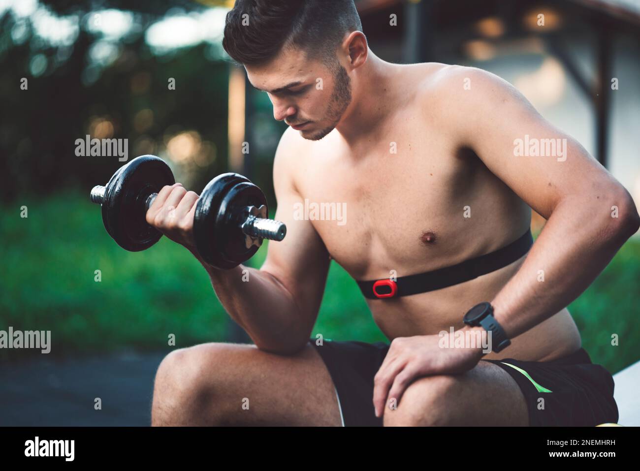 Fit caucasian man lifting weights outside, wearing a band around his ...