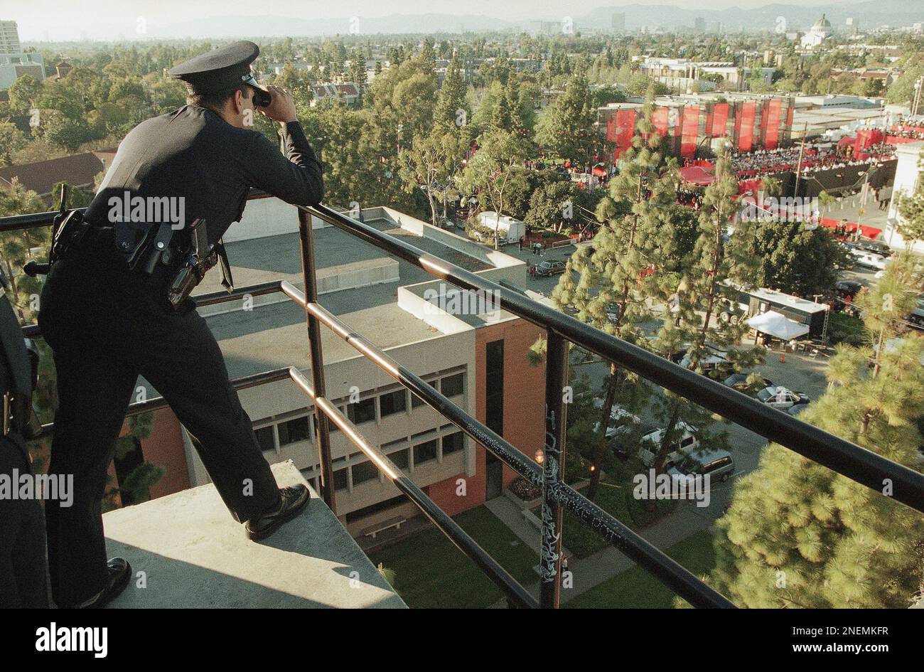 A Los Angeles Police officer looks through binoculars at the arrival of ...