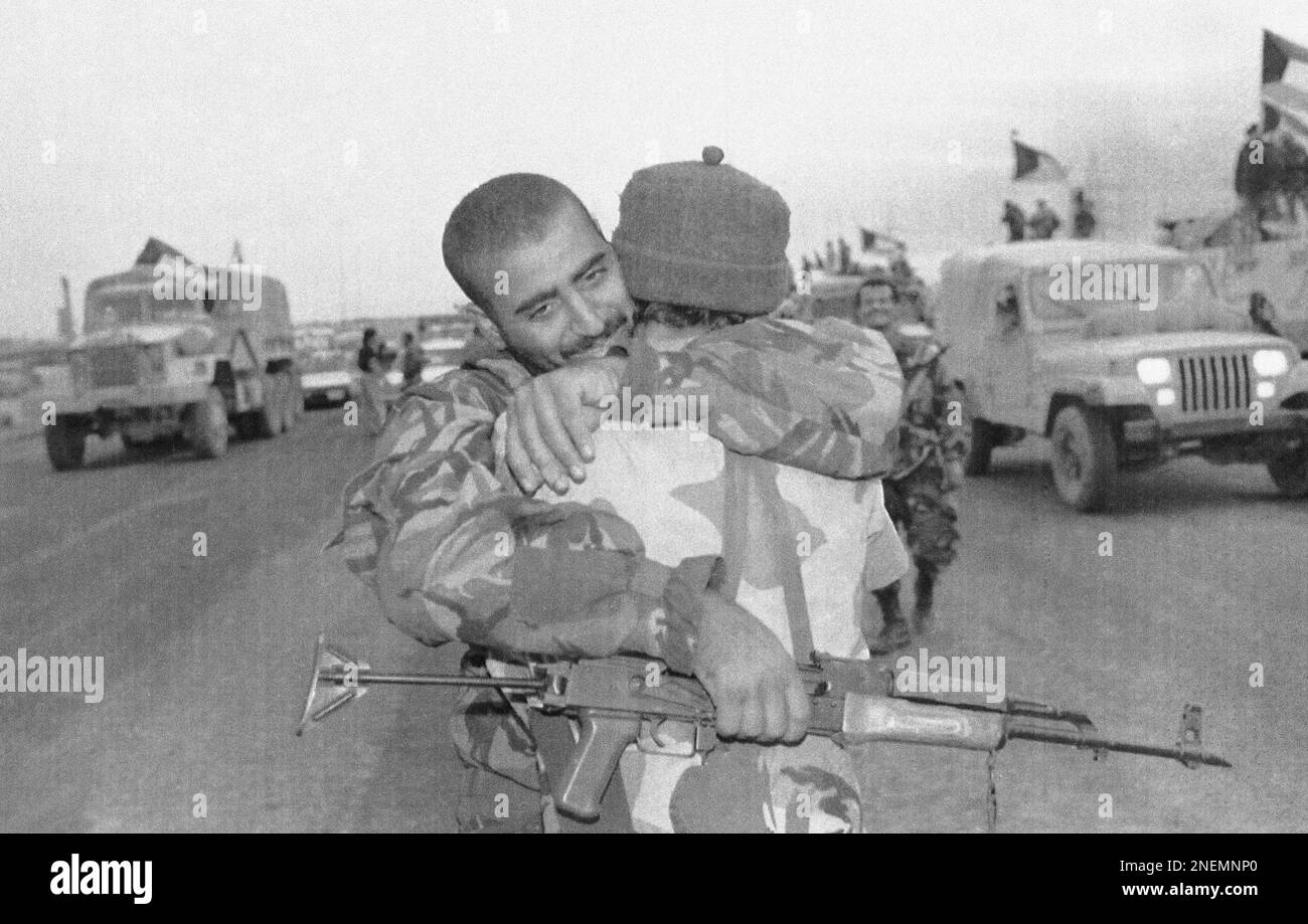 Two Kuwaiti soldiers, one armed with a Soviet-made AK-47, hug each ...