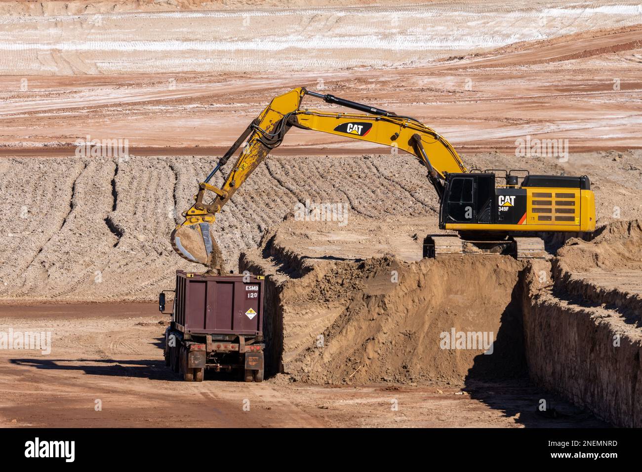 A heavy duty excavator loads a container truck with hazardous uranium ...