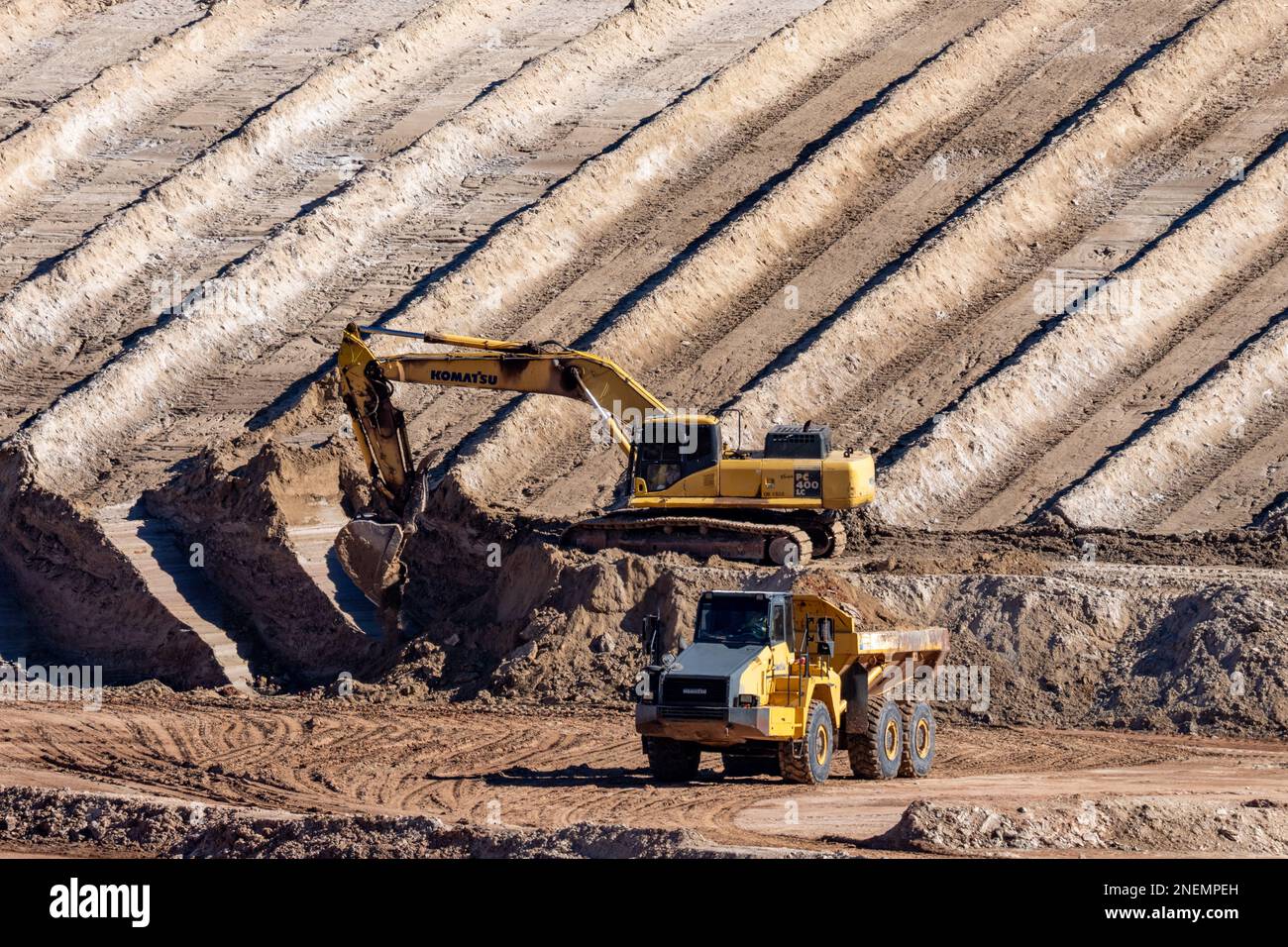 A heavy duty excavator loads a dump truck with hazardous uranium ...