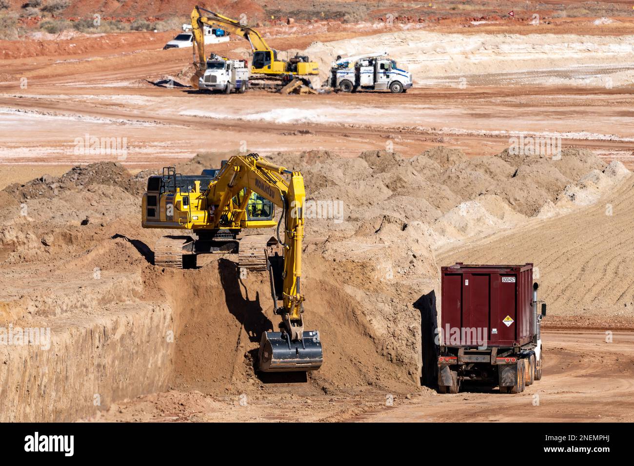 A heavy duty excavator loads a container truck with hazardous uranium ...