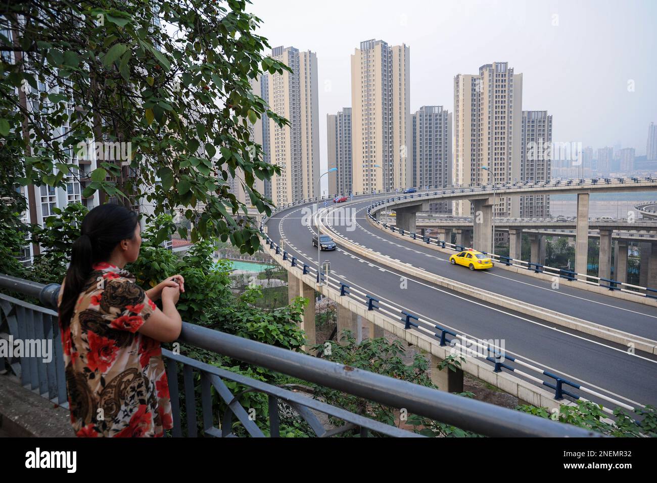 03.08.2012 2012, Chongqing, China, Asia - A woman looks at a new housing development with high ...