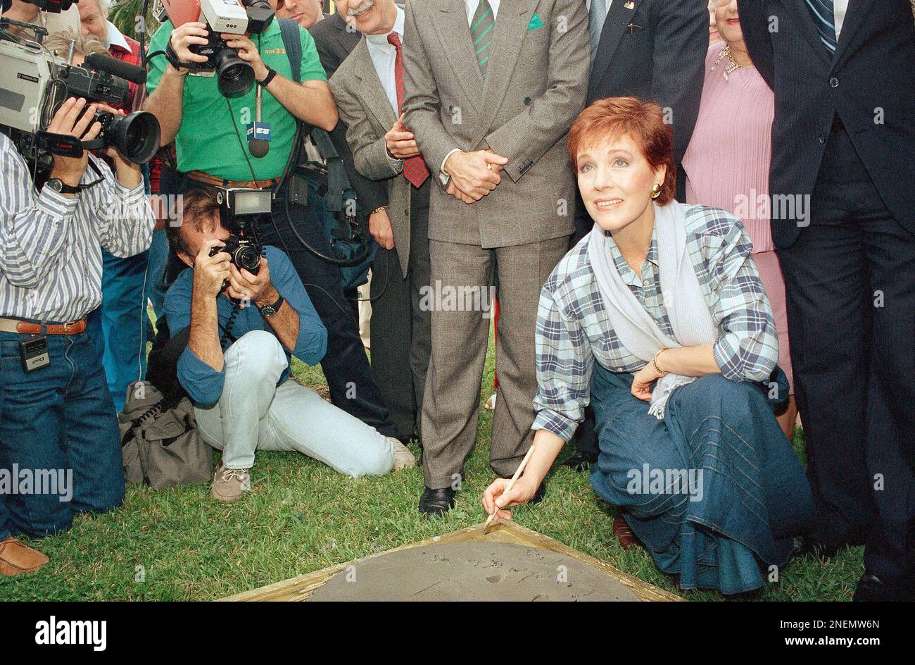 Actress Julie Andrews glances up after writing her name in concrete at ...