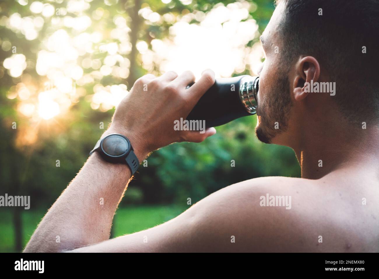 Over the shoulder view, man drinking water outside, wearing a smart watch on the wrist Stock ...