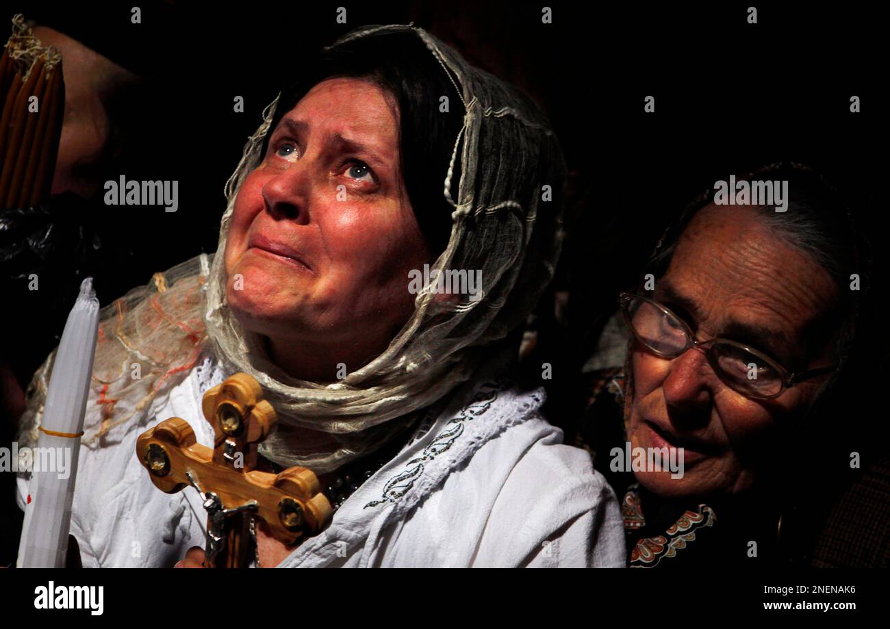 A Christian Orthodox pilgrim, left, weeps as she waits to see a beam of ...