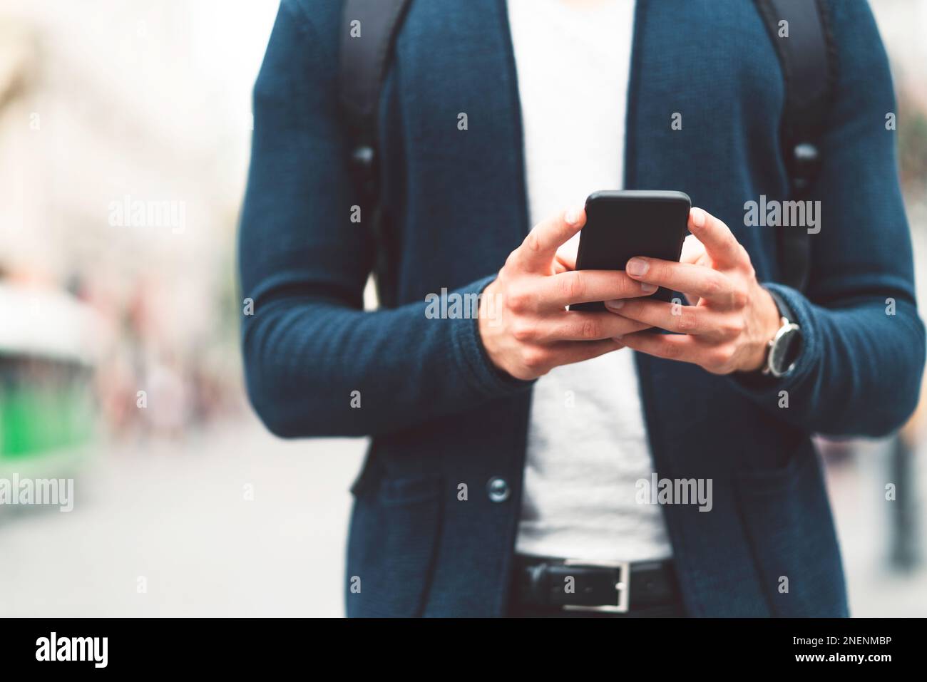 Unrecognizable man in blue sweater holding his phone with both hands ...