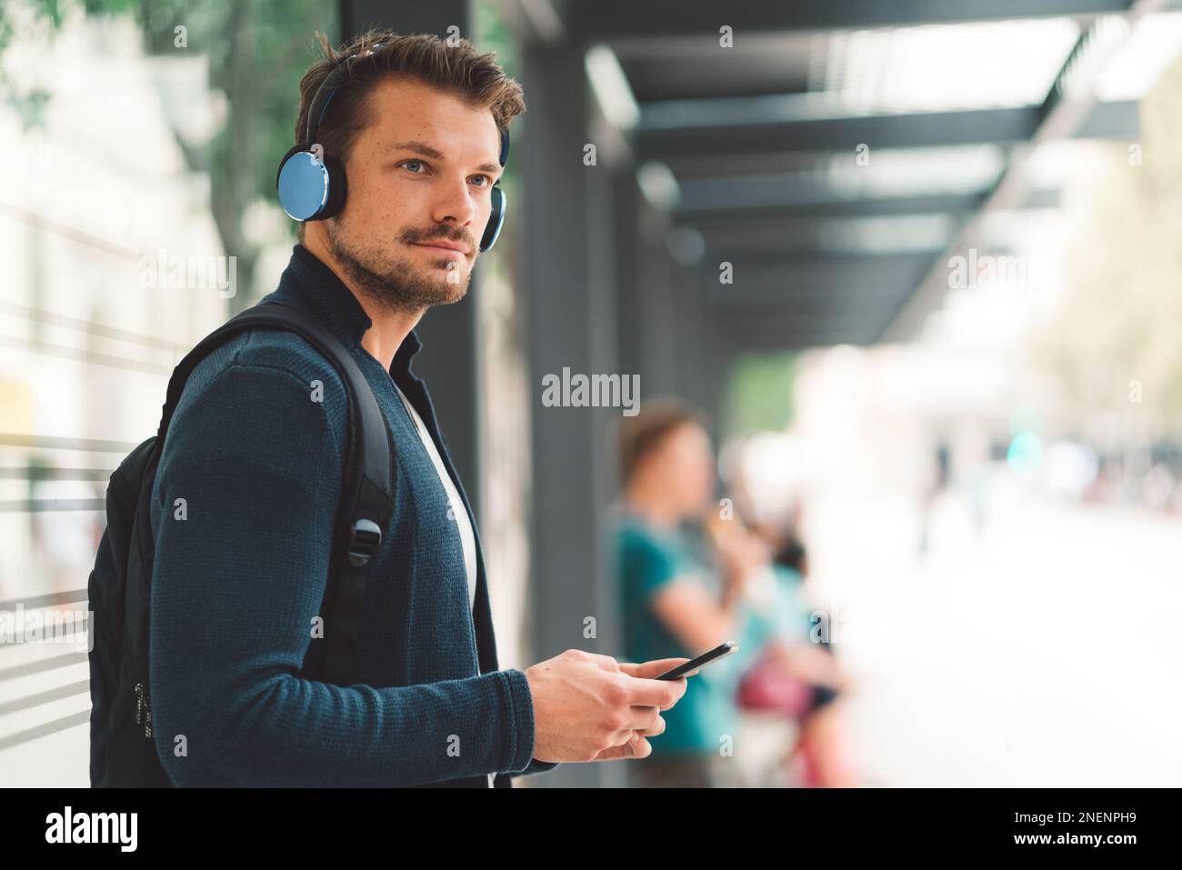 Wait up man with headphones listening to music at the bus station Stock ...