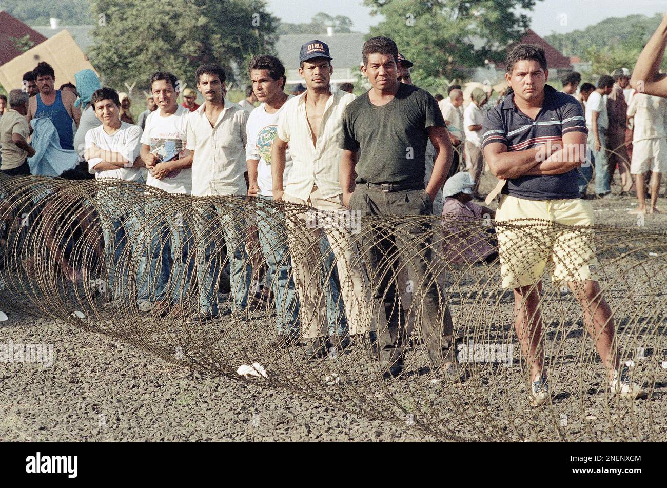 Panamanian detainees stand behind coiled barbed wire in a makeshift ...