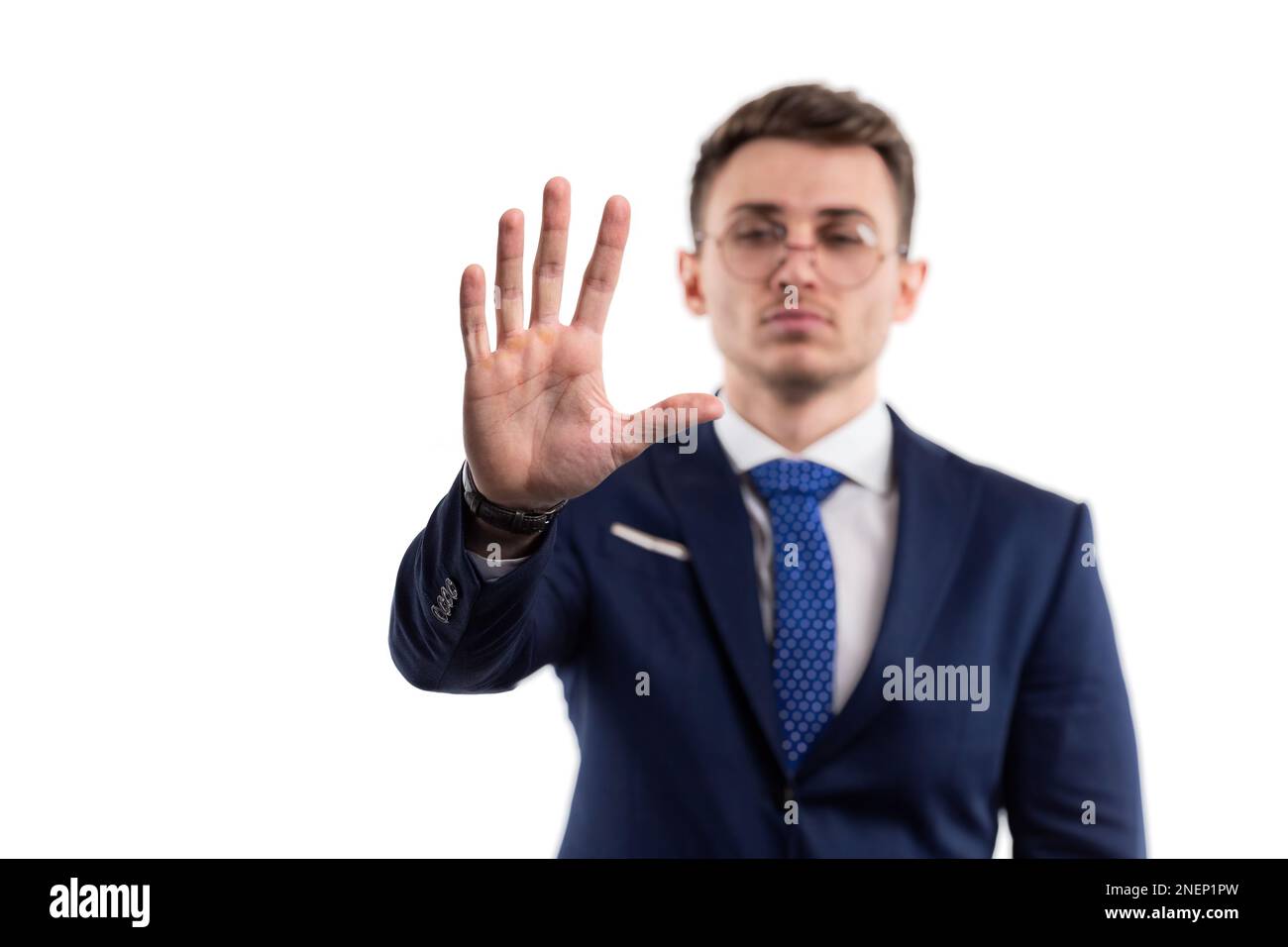 Man in a suit and tie makes a stop gesture with his hand showing his ...