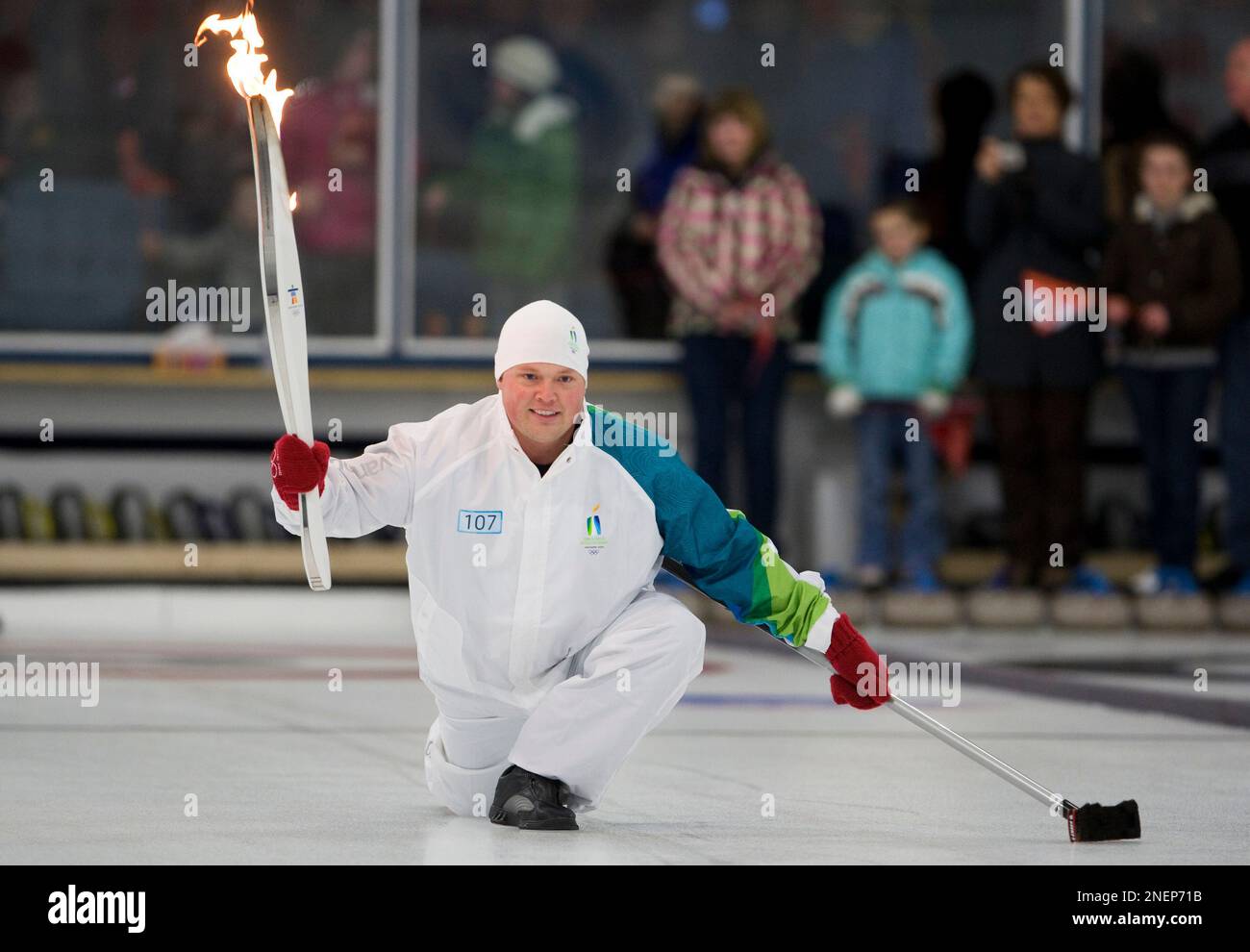 Torchbearer Mike Adam, an Olympic gold medalist in curling, slides on a ...